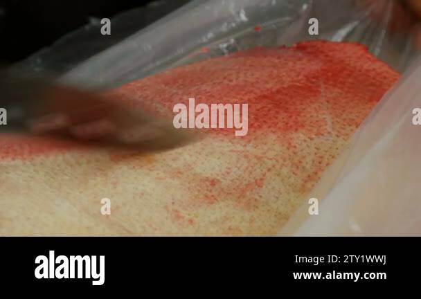 The butcher cleans the blood of large piece of pork carcass with a ...