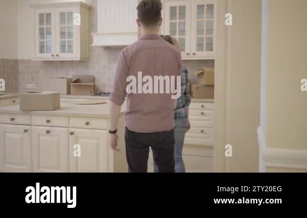 Bearded man and pretty woman enter the kitchen, holding hands. Man puts ...