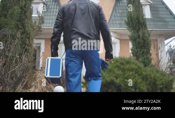 Back view of adult Caucasian man in headphones coming to the big house ...