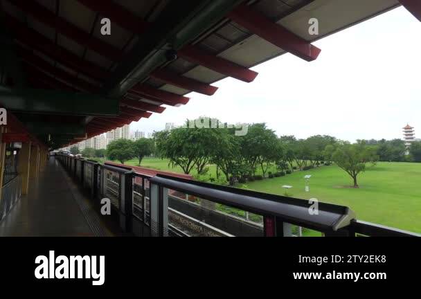 An MRT train in Singapore at the station on green trees background ...