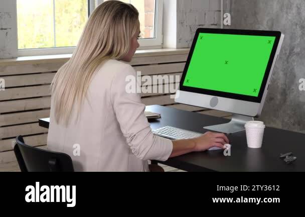 Business woman in dress sitting on workplace near the window and using ...