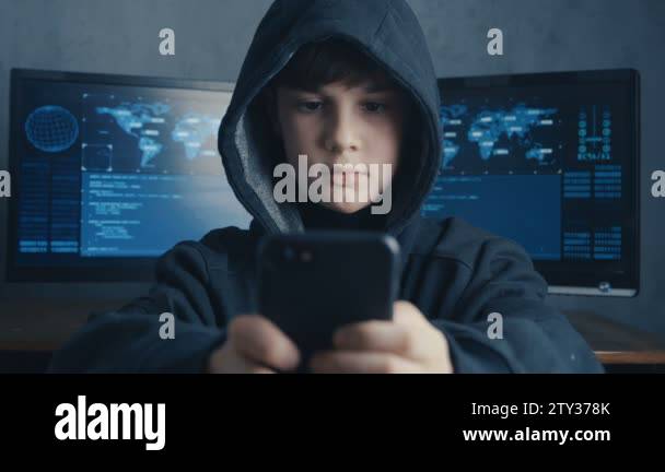 Young hooded hacker kid using a smartphone device to hijack. Genius boy ...