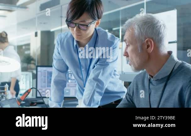 Two Engineers Talking while Working with Robot, Manipulating its ...