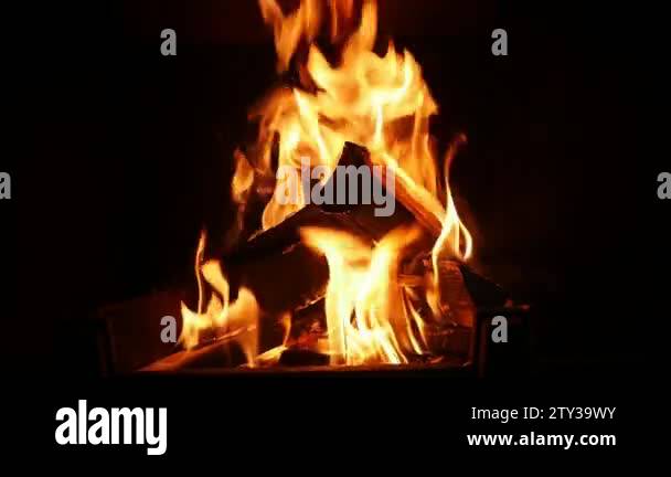 Live spurts of fire turning wooden logs into black ash in a fireplace ...
