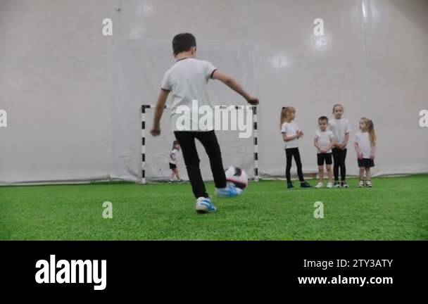 Indoor football arena. Little kids playing football. A little boy tries ...