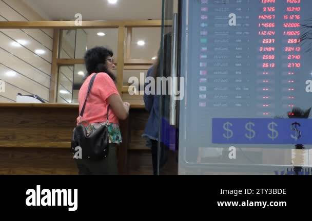 Two women changing money at bureau de change or currency exchange ...