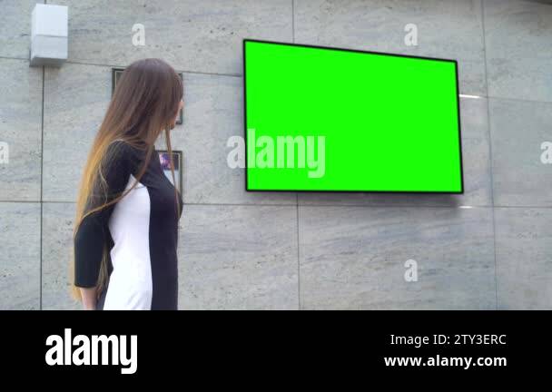 Young smiling business woman giving presentation on big green screen ...