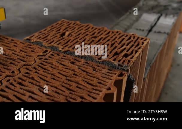 A construction worker removes excess cement from the joint of bricks ...