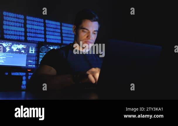 Portrait Of Developer Hacker Programmer Working On Computer In A Data Center Filled With Monitor