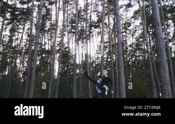 Young couple dancing in the forest on the background of beautiful pines ...