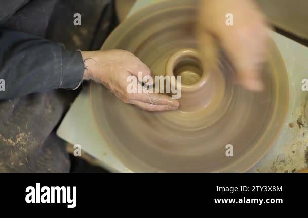 Potter forms a clay product with pottery tools on a pottery wheel, top ...