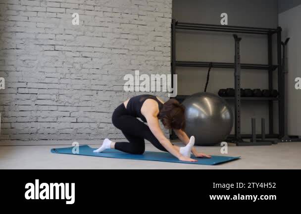 Yoga mat young athletic woman stretching hip, hamstring muscles, leg ...