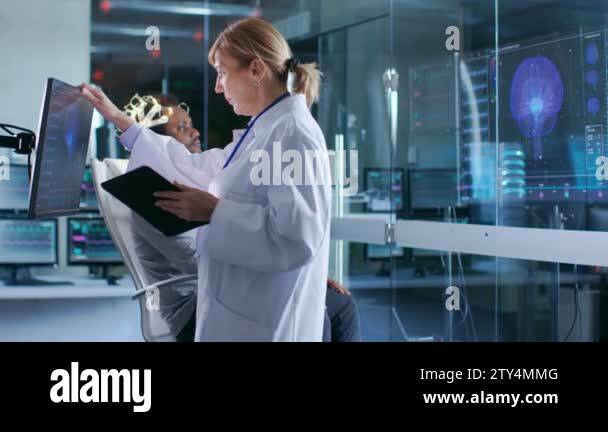 Man Wearing Brainwave Scanning Headset Sits in a Chair while Scientist ...