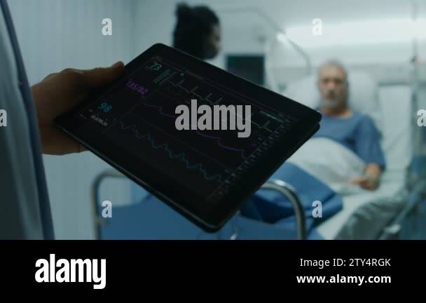 In the Hospital Doctor Holds Tablet Computer Showing Vital Signs of a ...