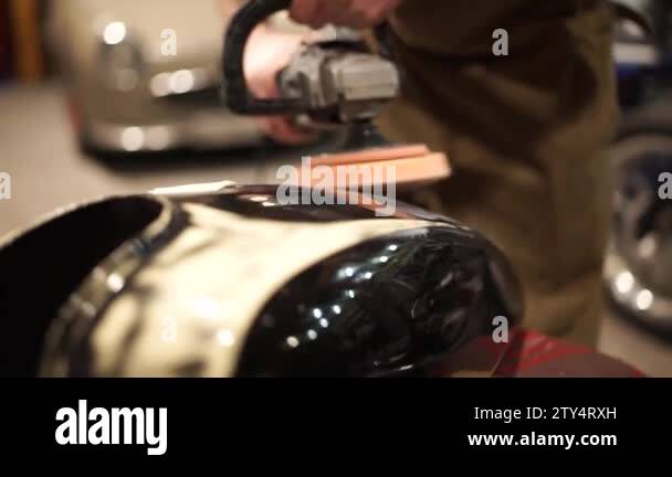 Guy polishing metal gas tank with sandpaper. Auto mechanic assembles ...