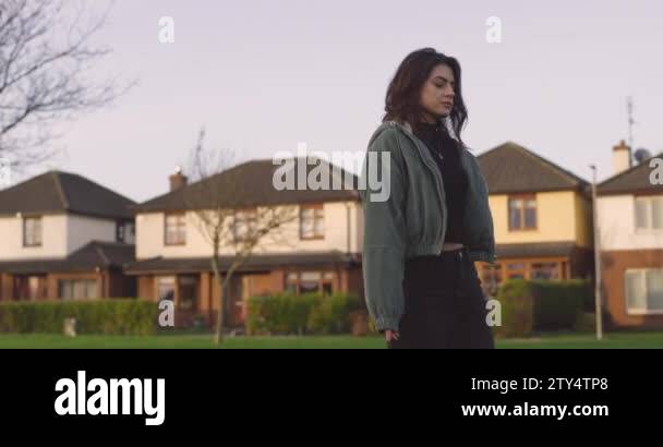 Beautiful brunette lady with a sad face and very pensively walking down the street on a estate ...