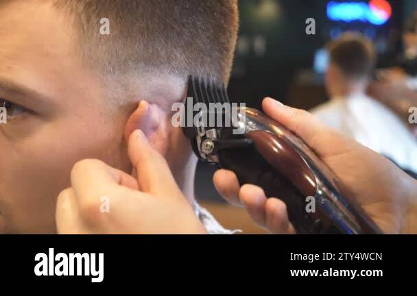 Close up arms of barber making male haircut to customer with clipper in ...