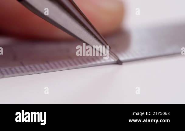 Man drawing a line on white blank with iron ruler and brush pen. Close ...