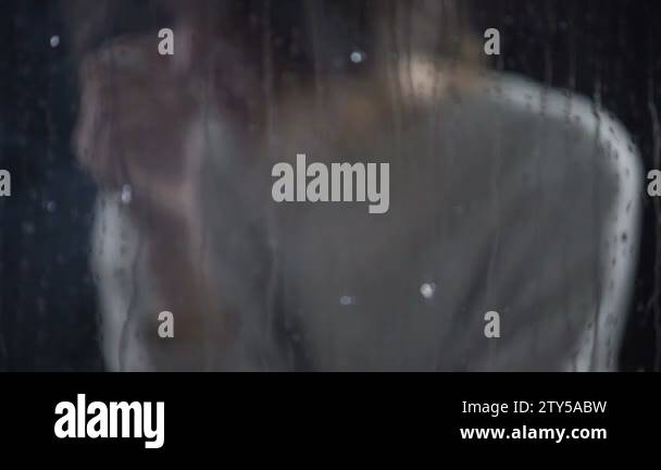 Crying miserable woman smoking cigarette behind rainy window ...