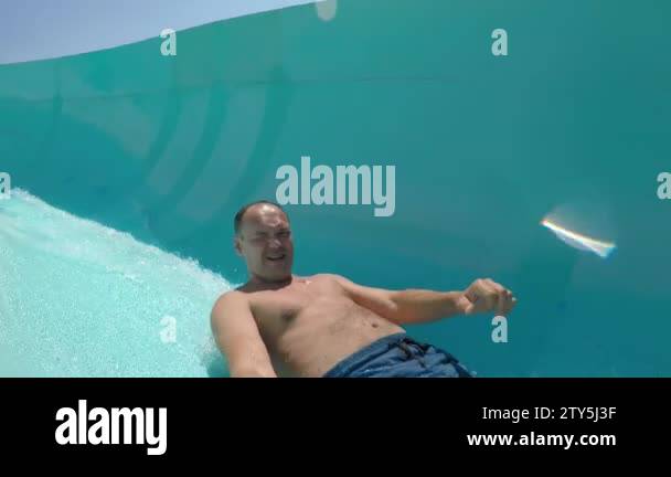 Middle-aged man sliding a water flume and taking a selfie happily in ...