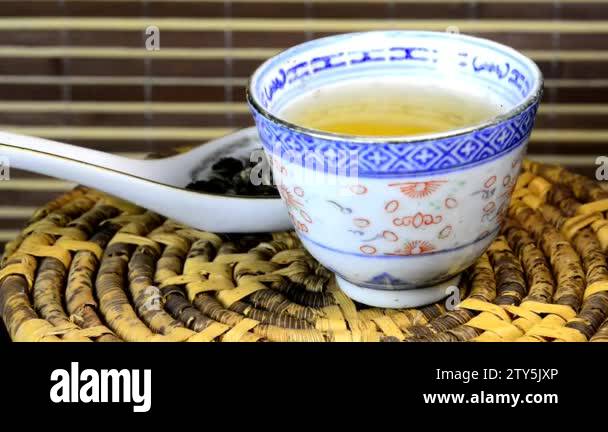jasmine tea in a Chinese bowl and dried gun powder on spoon on a turn ...