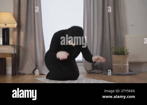 Young Muslim lady in black traditional hijab bowing down and raising up ...