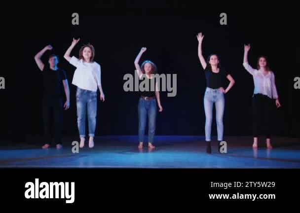 A theater stage. People jumping on the stage with a raised up finger ...
