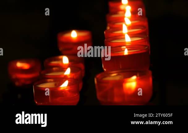 Row of christian prayer red round votive candles burn in the dark ...