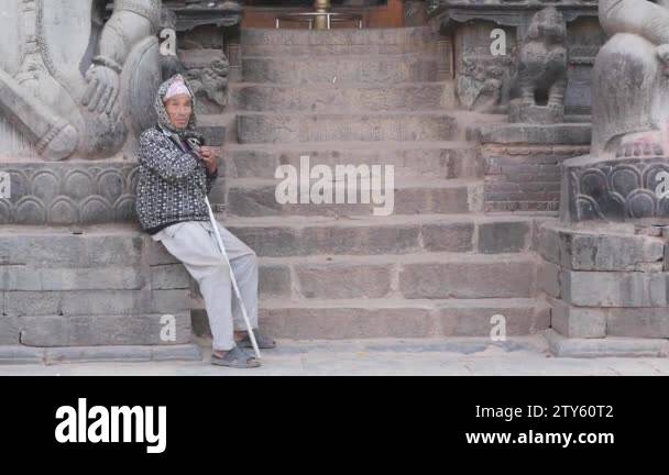 BHAKTAPUR, KATHMANDU, NEPAL - 18 October 2018 Poor man on stone steps ...