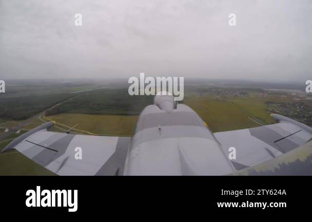A gray blue combat plane fly over a road in field and rolls to the left ...
