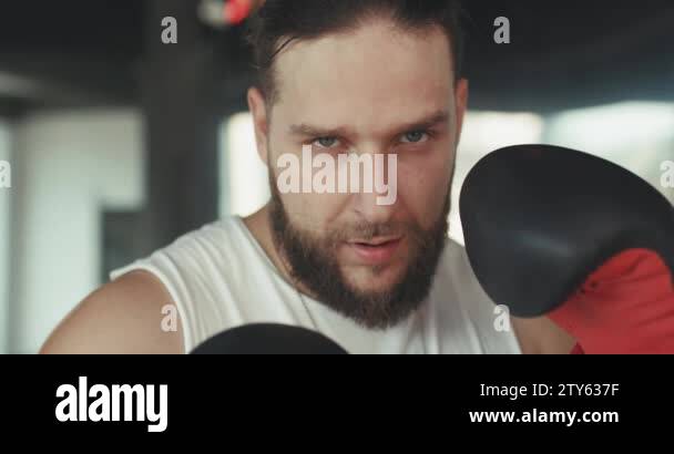 Young serious man standing shirtless on boxing ring and looking at the ...