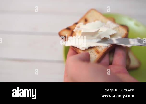 Detail of male hands spreading butter over a toasted bread slice ...