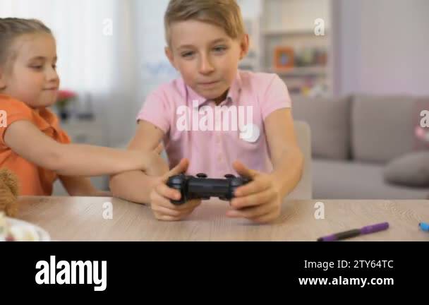 Little girl disturbing brother playing console game, children fighting ...