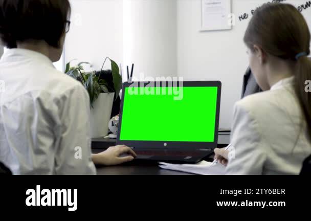 Young women working in office, sitting in chairs in front of computer ...