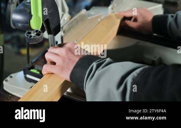 Close up mans hands carpenter installs a wooden workpiece in a circular ...