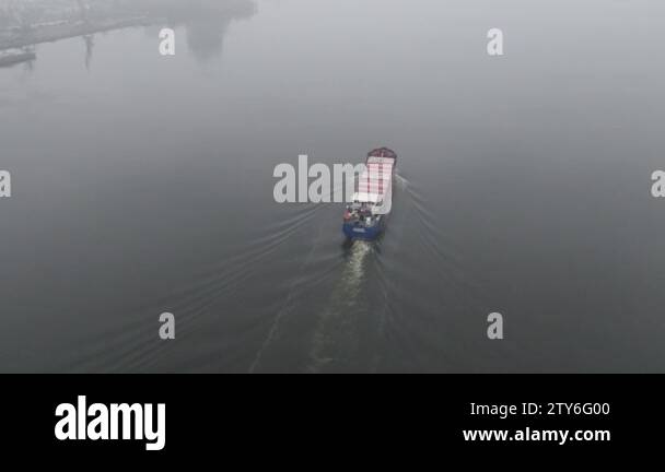 A barge loaded with scrap metal and waste floating on a water surface ...