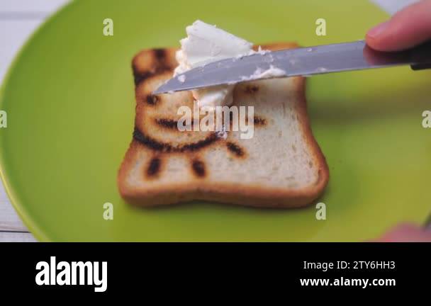 Detail of male hands spreading butter over a toasted bread slice ...