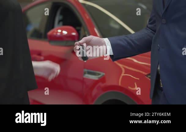 Unrecognized salesman in a business suit gives a car keys to ...