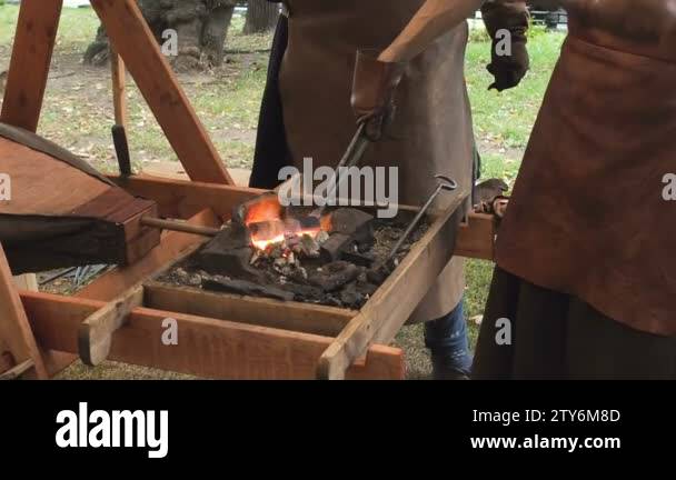 The blacksmith holds the billet over hot coals in a clay oven ...