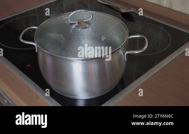 Putting raw pasta in a boiling water - a hand taking off a hot lid from ...