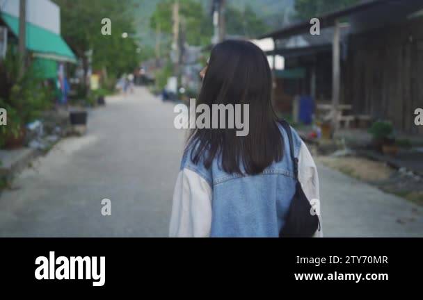 Back view of attractive long-haired brunette woman walking down the ...