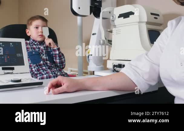 Ophthalmologist treatment in the clinic - a little boy covers his eye ...