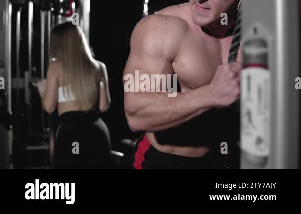 Couple of bodybuilders in gym train arms triceps muscles using cable ...