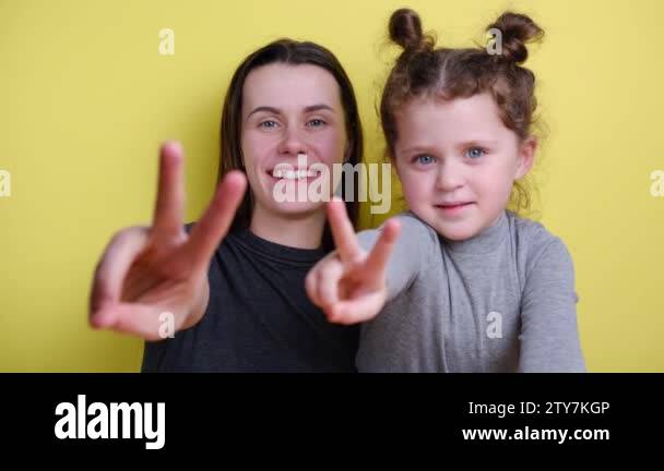 Happy cheerful mother and kid girl waving hands looking at camera ...