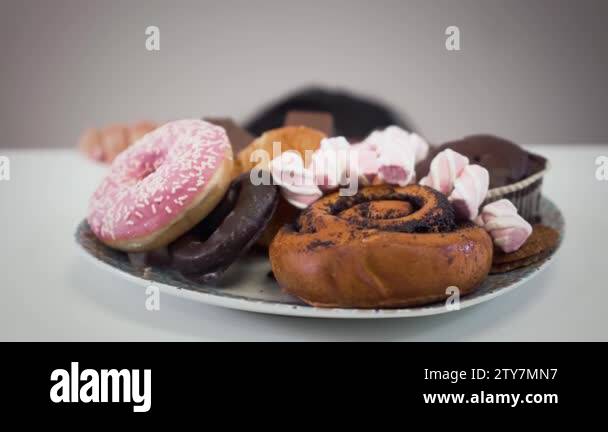 Plate with sweets standing on the table, obese Caucasian woman ...
