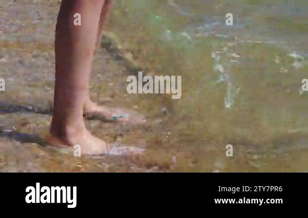 Girl on summer holiday on tropical sand beach dips her feet in the ...