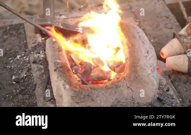 The blacksmith holds the billet over hot coals in a clay oven ...
