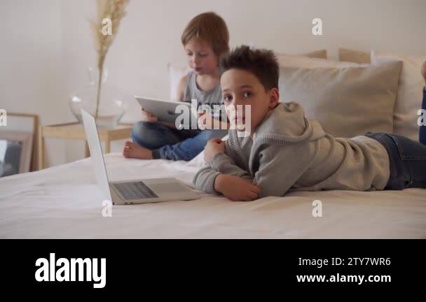 Boys in parents bed at morning with laptop and tablet. Brothers play ...