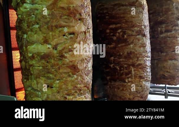 A pair of rotating skewered chicken and lamb meat grilled and ready to ...
