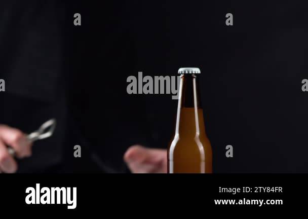 Men opening cold bottle of beer with cap on black background. Hands ...